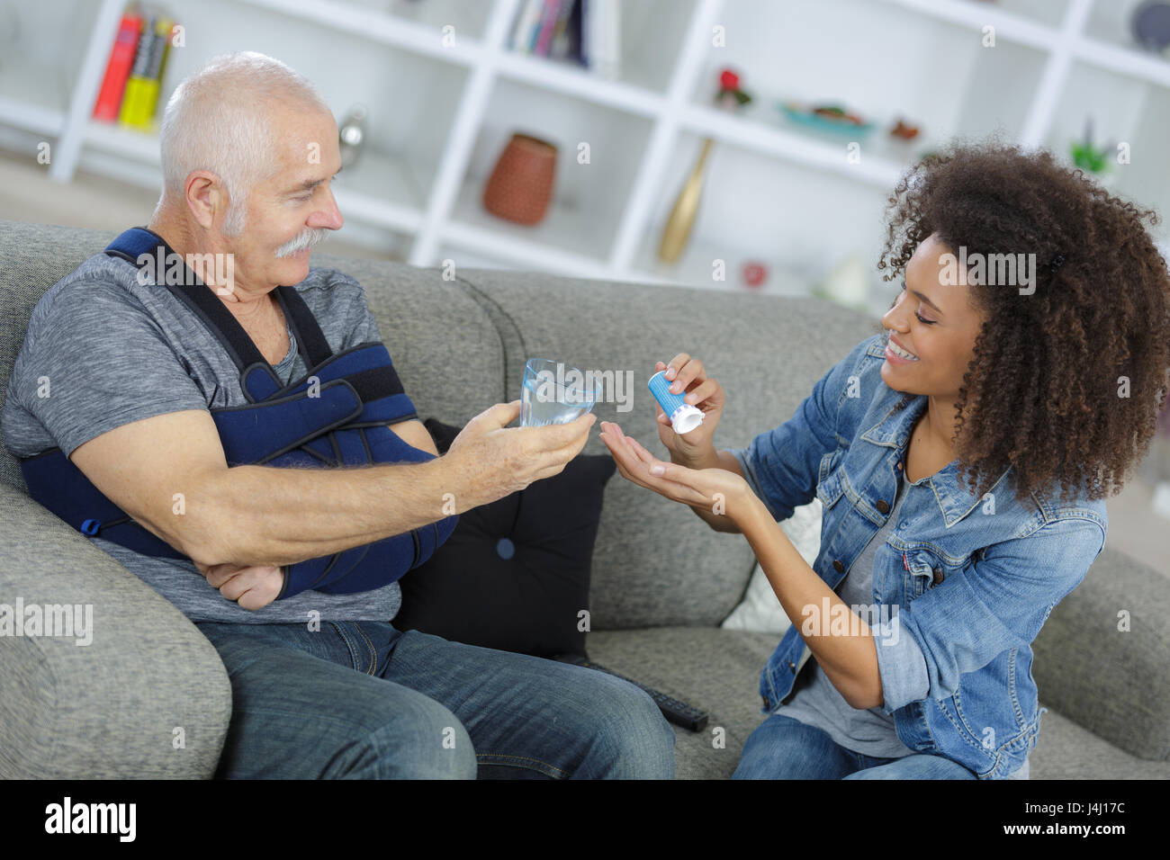 Lady preparing medication for senior man with his arm in a sling Stock ...