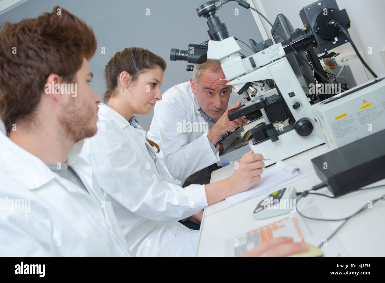 Teacher instructing students on use of microscope Stock Photo - Alamy