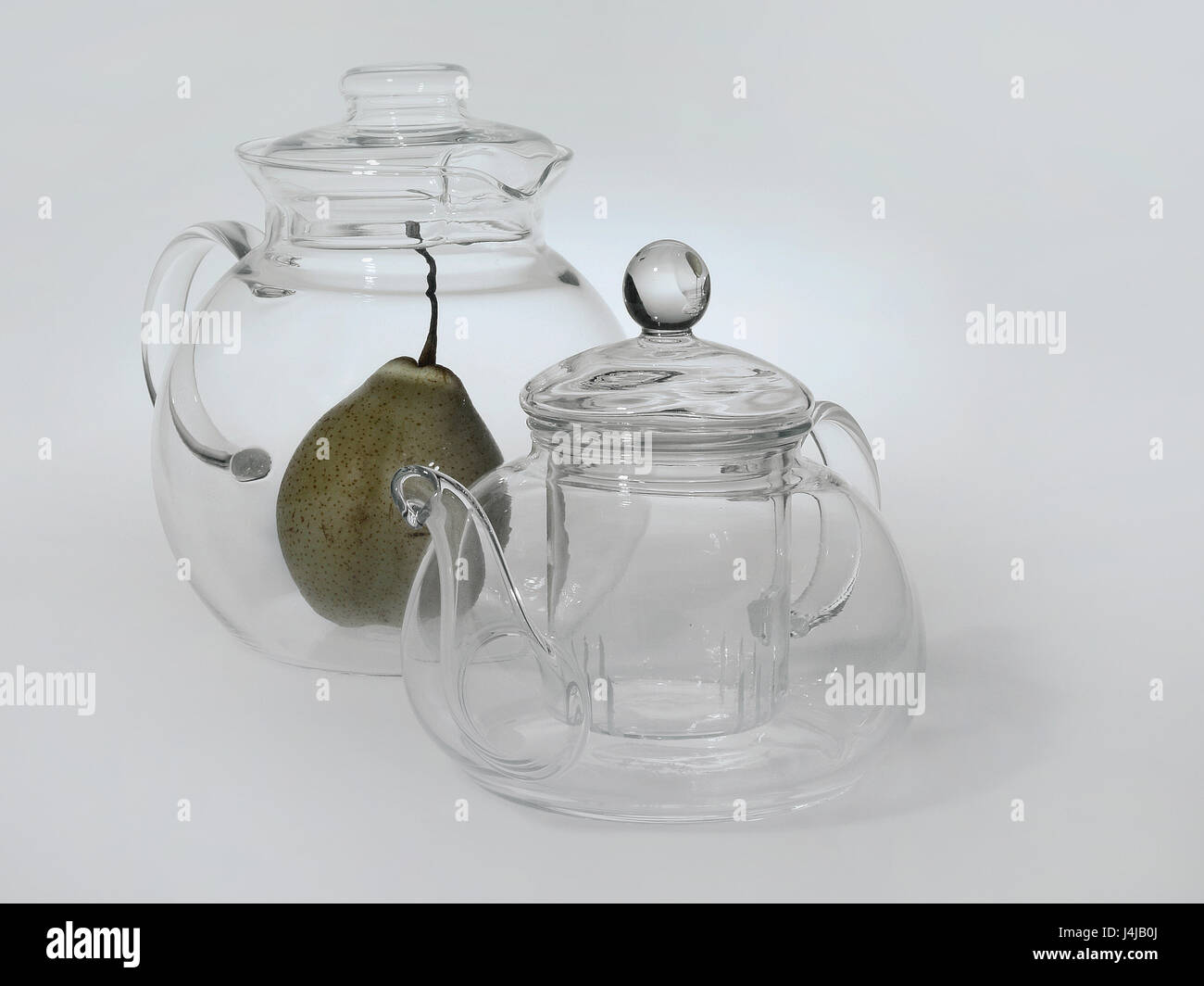 Two glass transparent teapots stand next to each other, inside a large ...