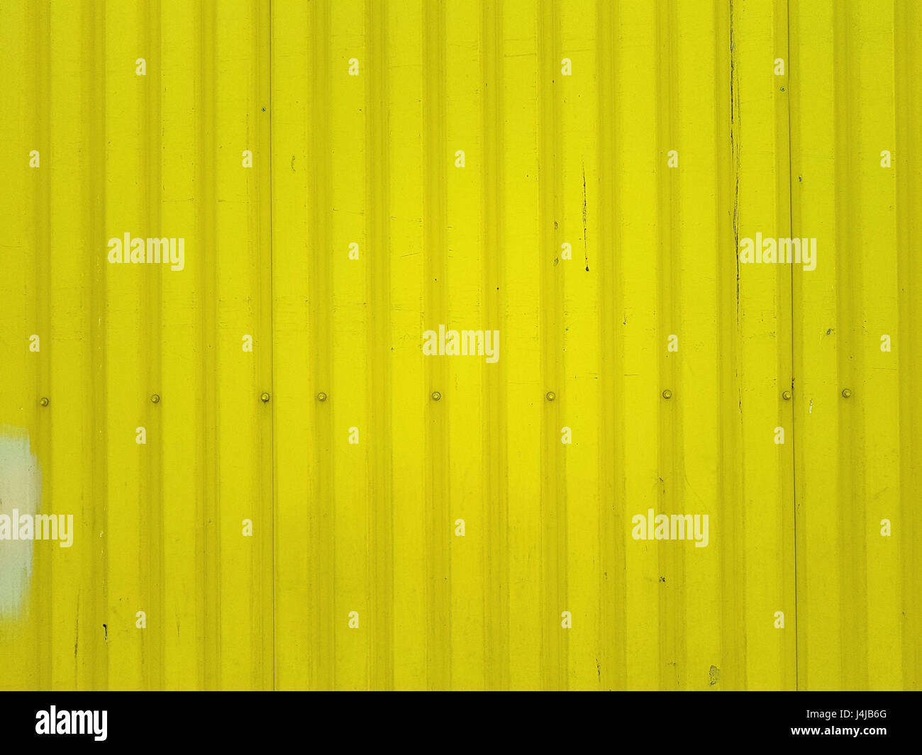 Bright yellow tin wall background texture with screws in the lower part ...
