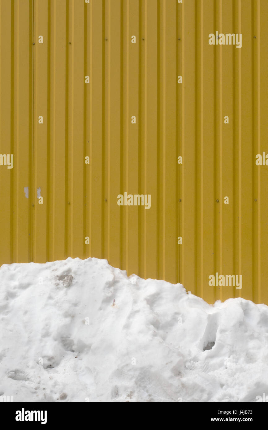Dark yellow striped metal wall, the bottom one-third of the frame white ...