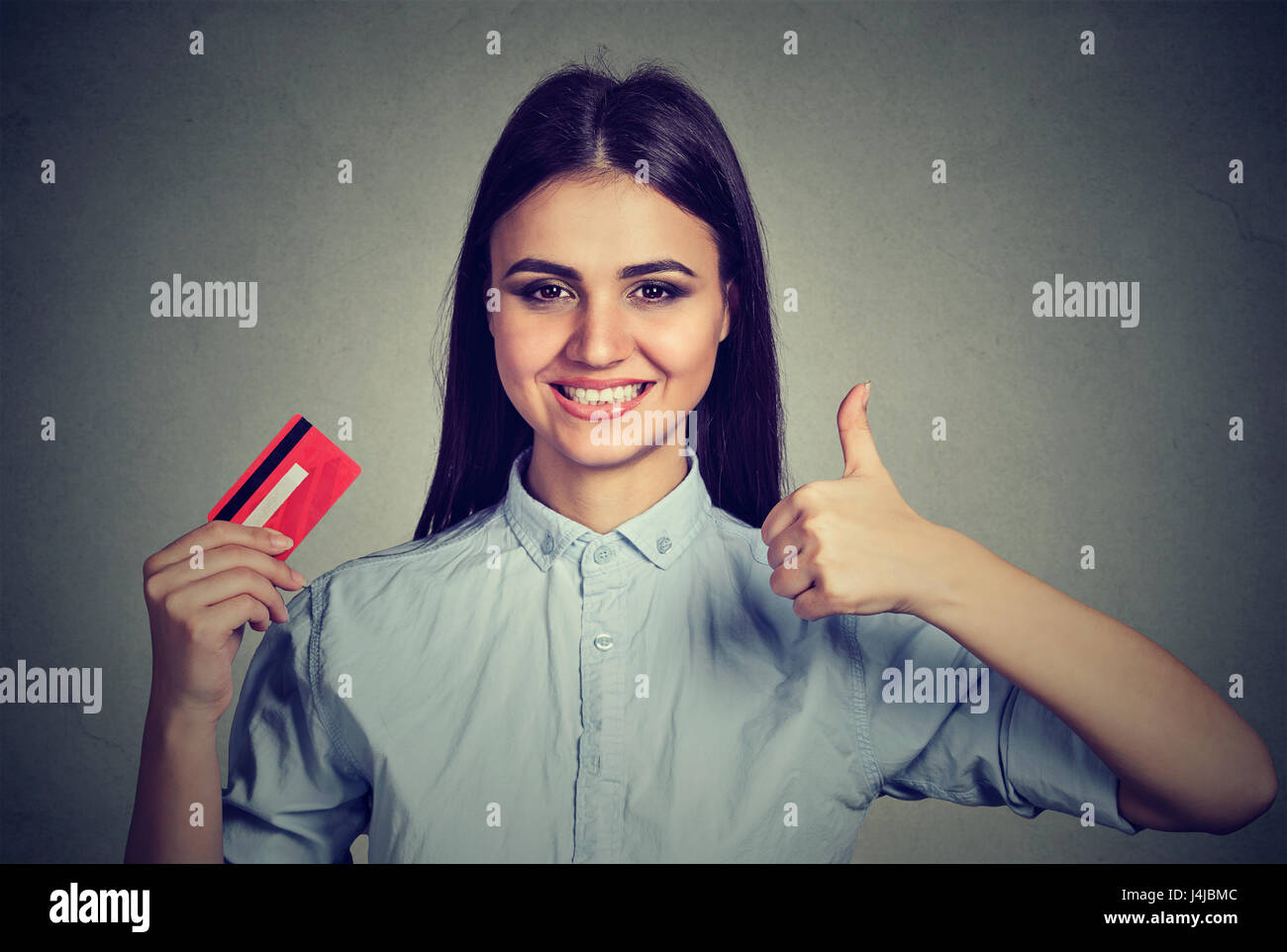 Smiling woman holding a credit card giving thumbs up Stock Photo - Alamy