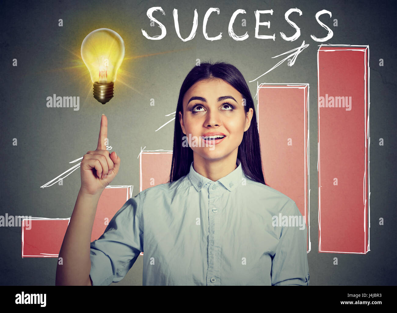 Successful woman looking up at bright idea light bulb with growing ...