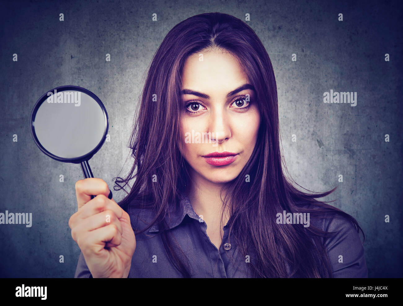 Beautiful woman with magnifying glass isolated on gray wall background ...