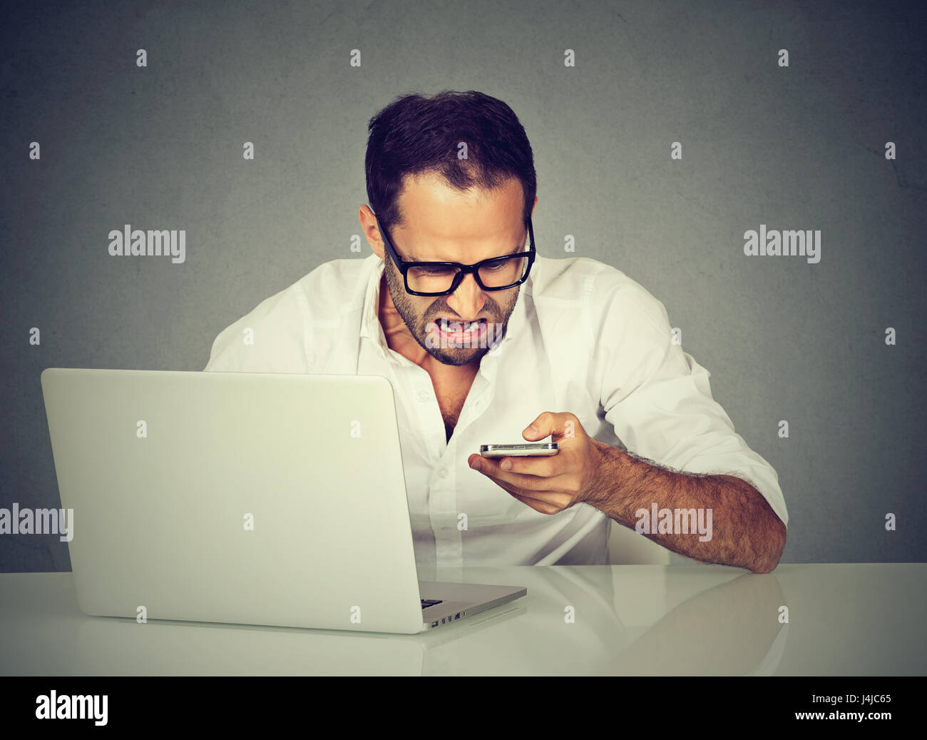 Angry stressed man having problems on line with a laptop talking ...