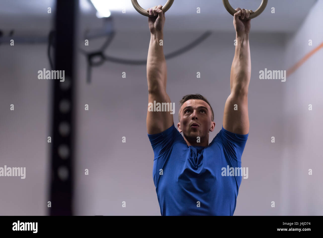 Fitness handsome man doing dipping exercise using rings in the gym ...