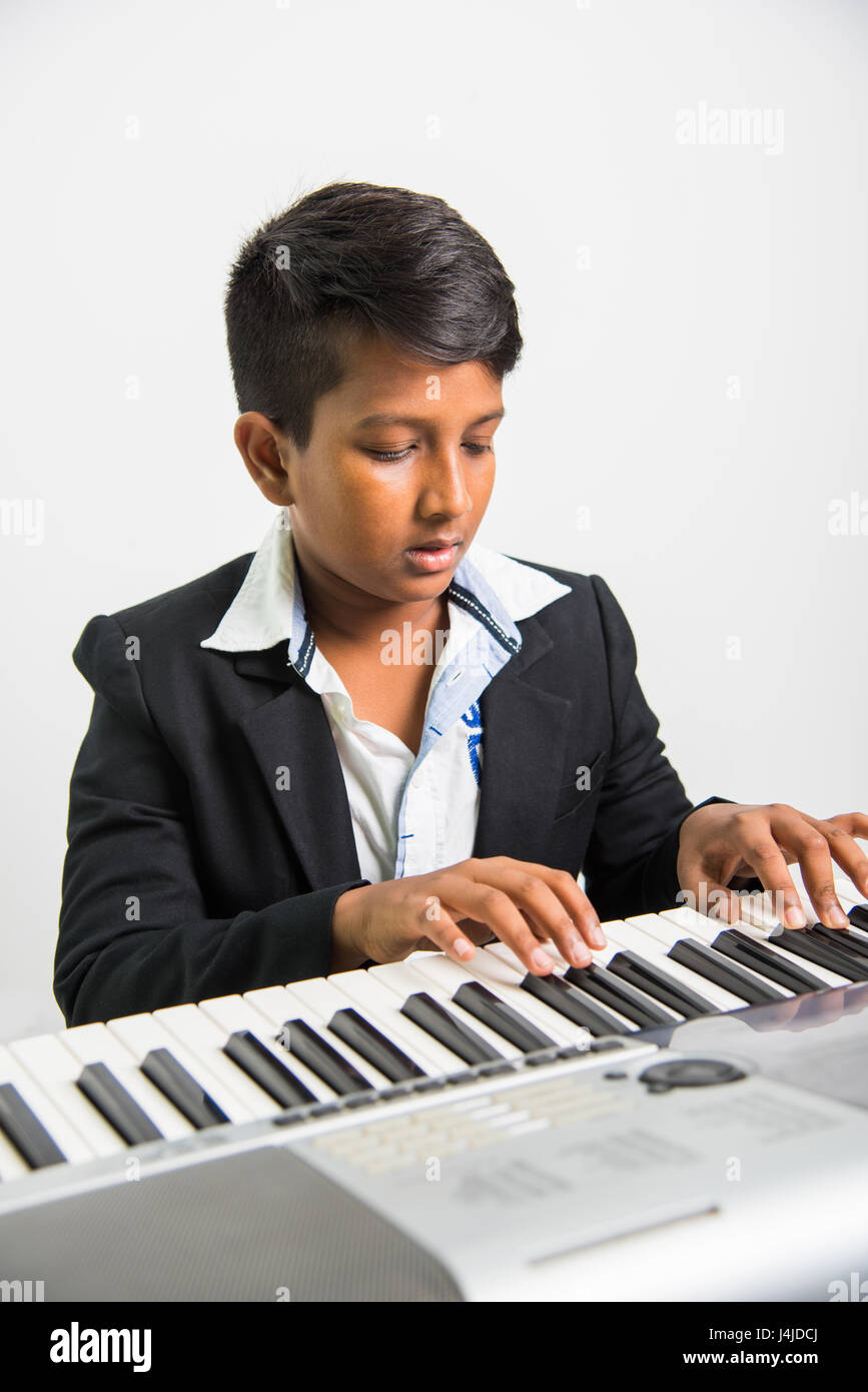 Cute little Indian/Asian boy playing piano or keyboard, a musical ...