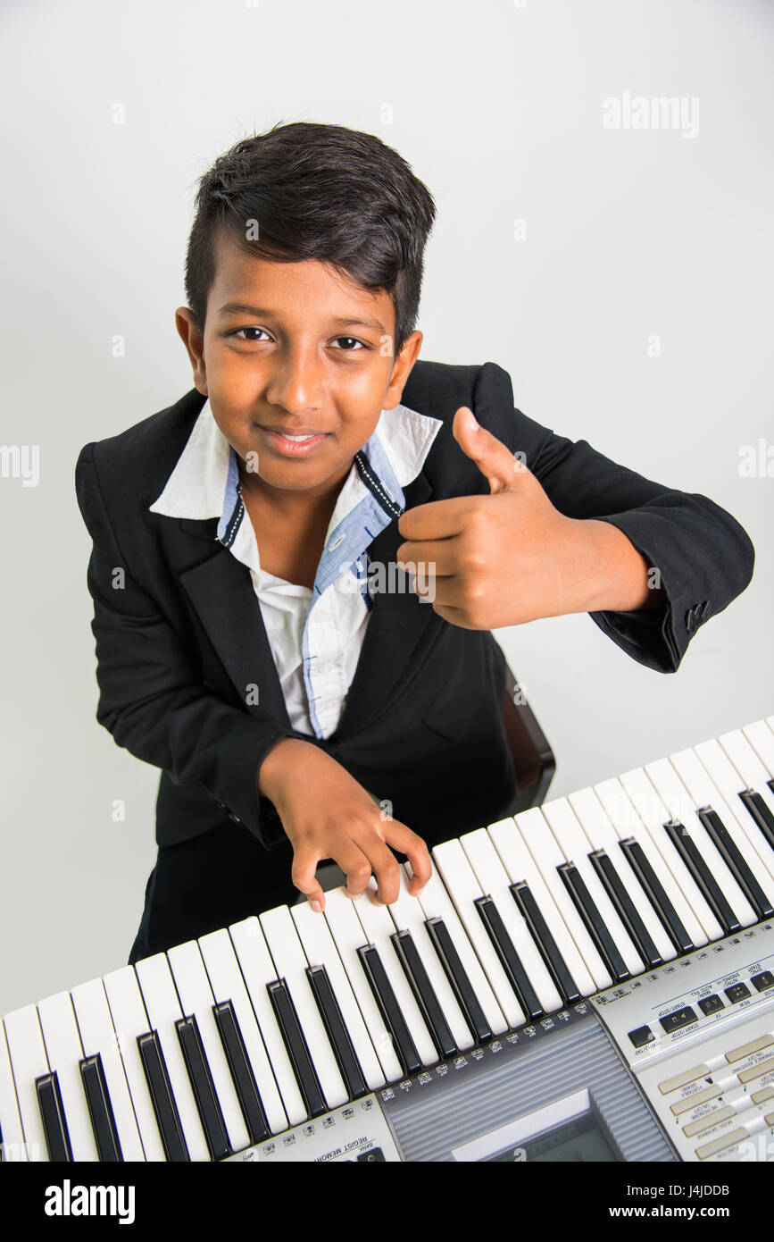 Cute little Indian/Asian boy playing piano or keyboard, a musical ...