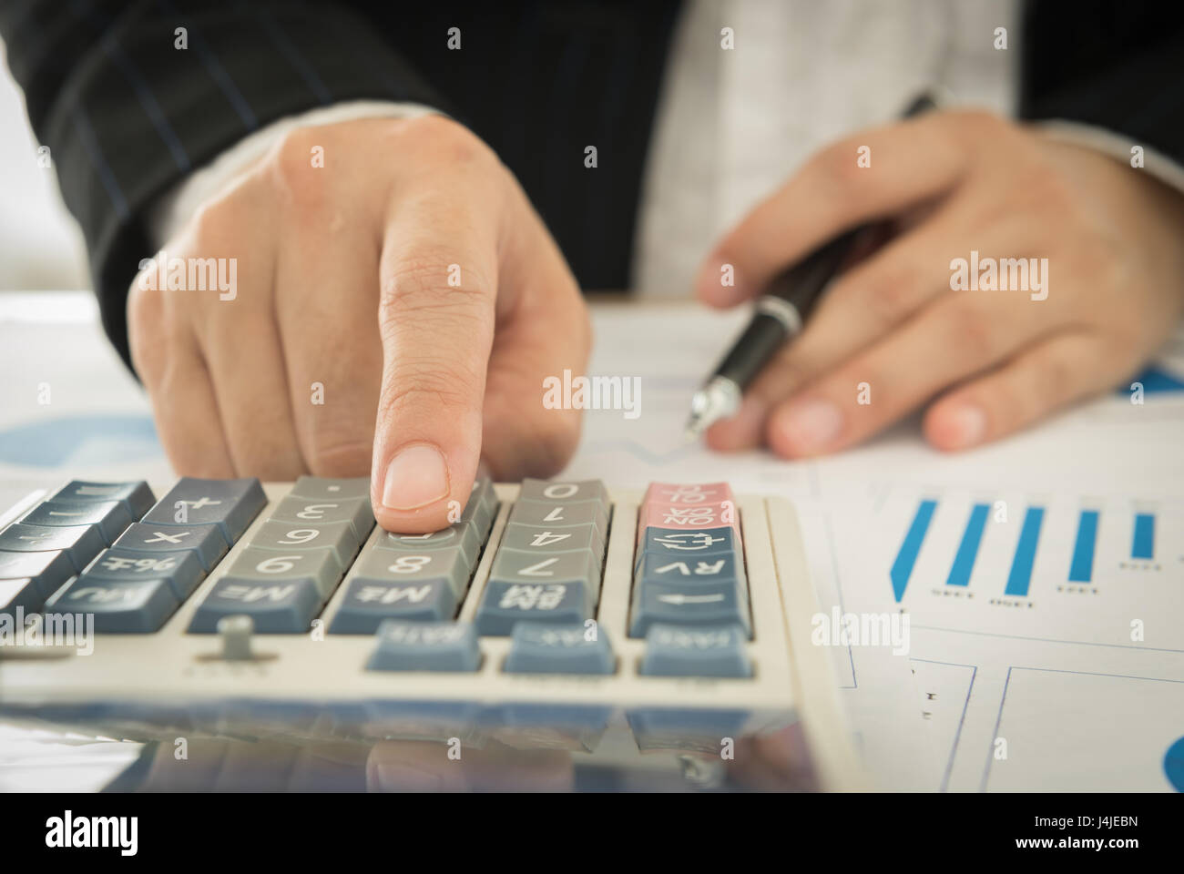 Businessman using a calculator to calculate the numbers Stock Photo - Alamy