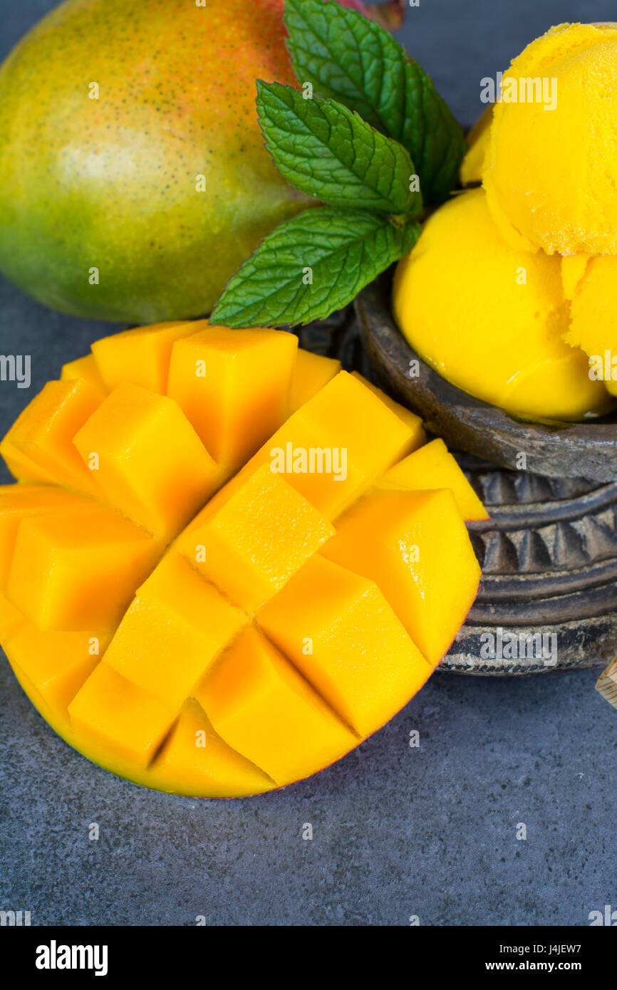 Mango ice cream sorbet with mint leaves and mango fruit in black stone ...