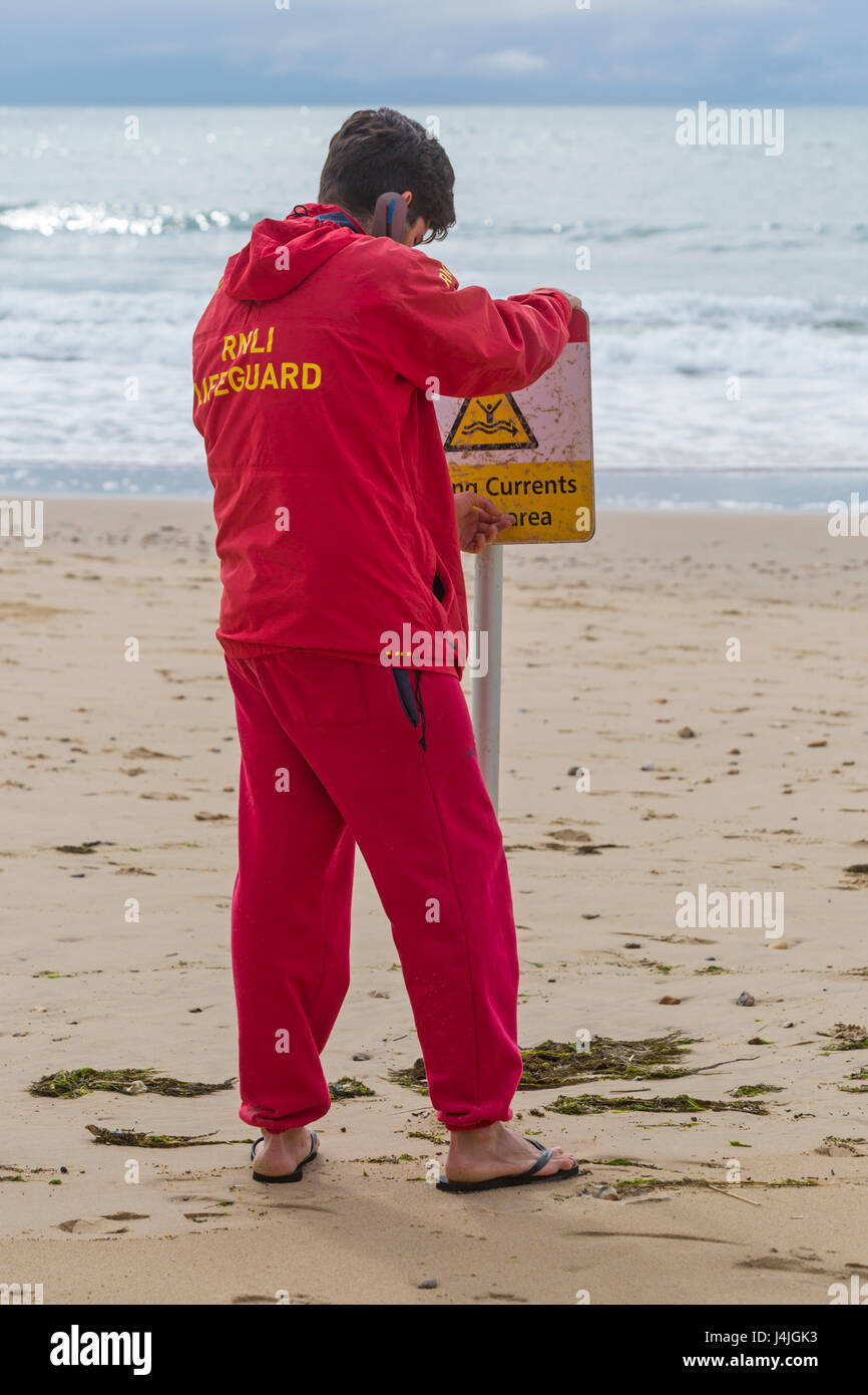 RNLI Lifeguard securing the strong currents in this area sign at the ...