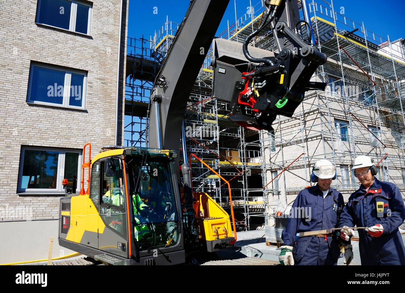Construction workers on site with digger Stock Photo - Alamy