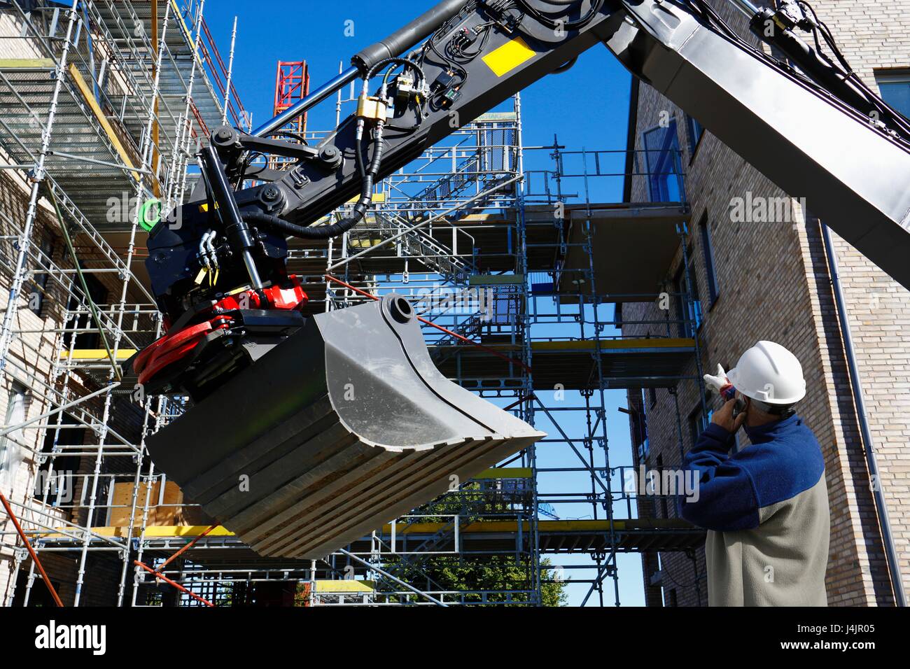 Construction worker on site with digger Stock Photo - Alamy