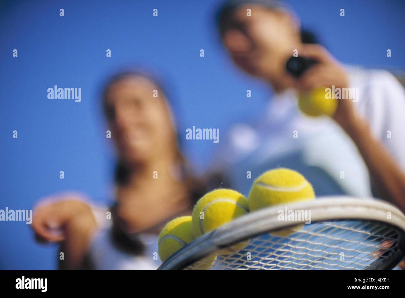 Couple, arm in arm, tennis racquet, balls, from below, blur outside ...