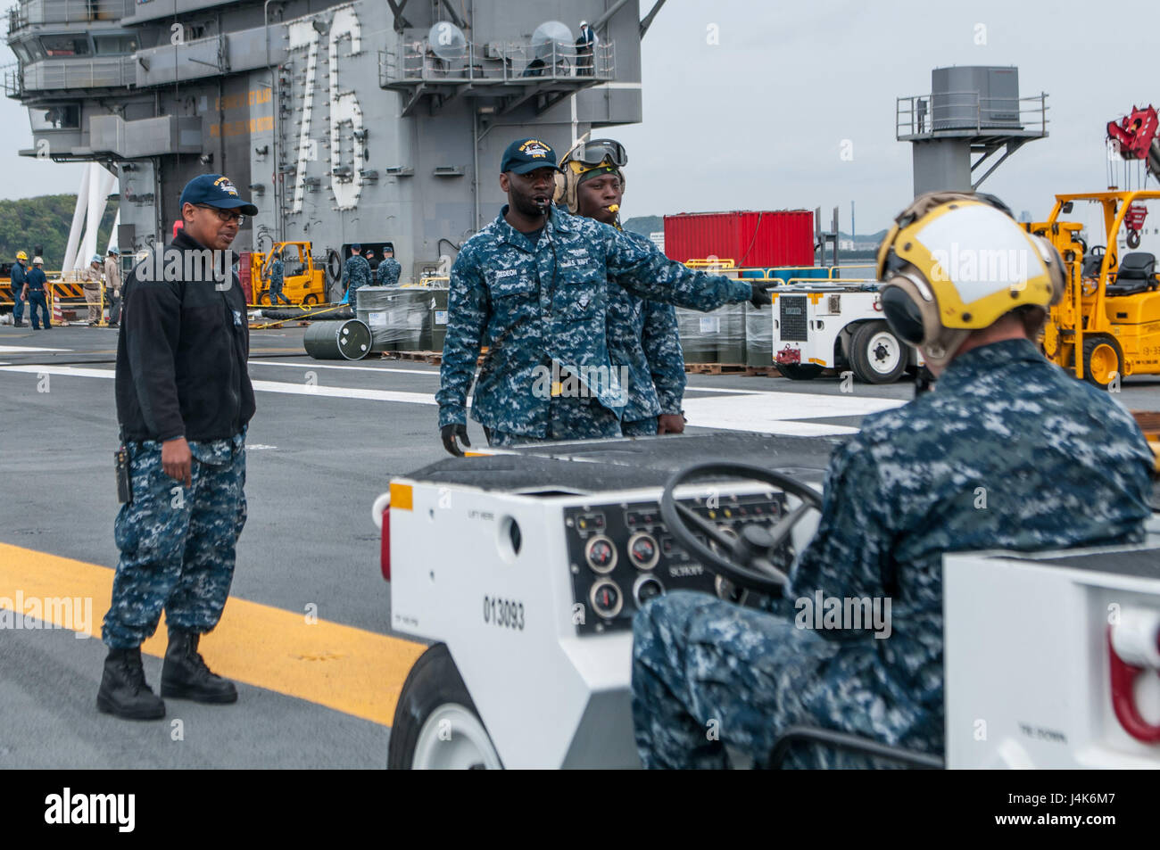 Aviation Boatswain's Mate directs a tractor driver during aircraft ...