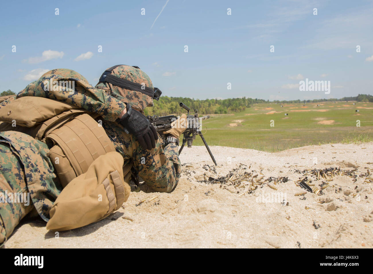 A Marine pulls the charging handle of an M249 light machine gun in ...