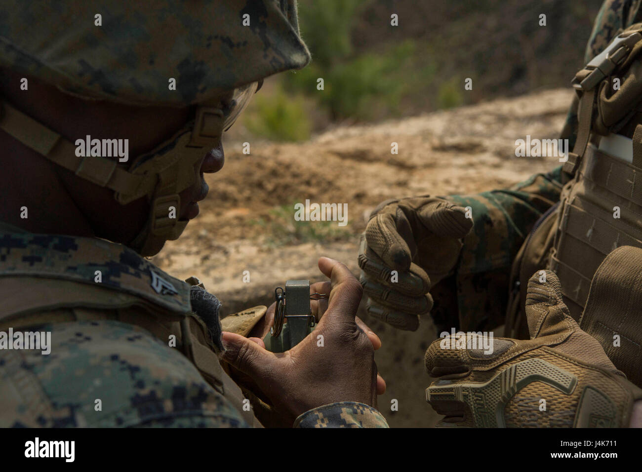 A Marine prepares to remove the first safety clip of an M67 ...