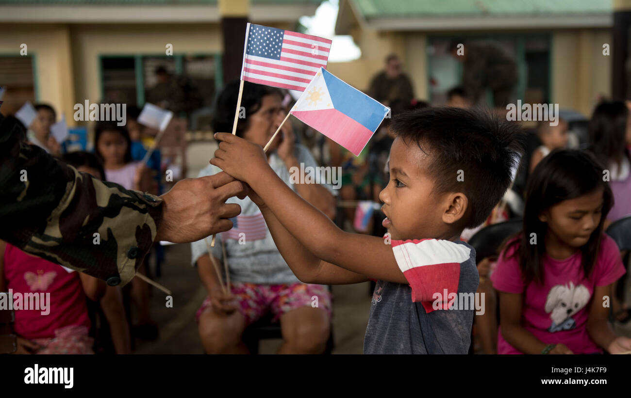 A Philippine Soldier gives a young student a Philippine and U.S. flag ...
