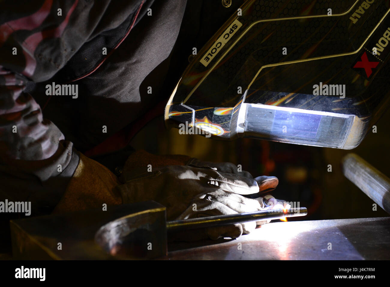 A U.S. Army transportation specialist welds a bolt to a metal rod at ...