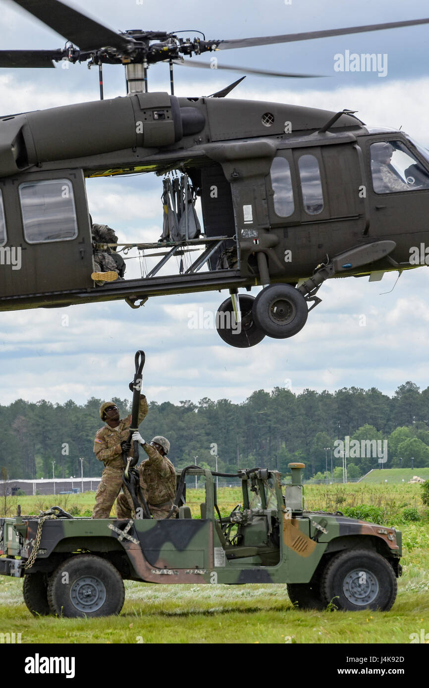 Soldiers hook a Humvee to a UH-60 Black Hawk during a sling-load ...