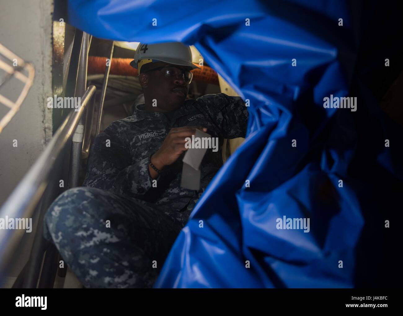 Airman sets up a ladderwell barrier aboard USS John C. Stennis during ...