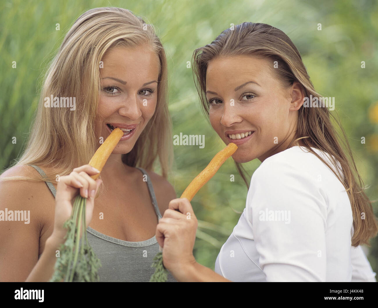 Women, happily, carrots, eat, portrait outside, summer, young, two ...