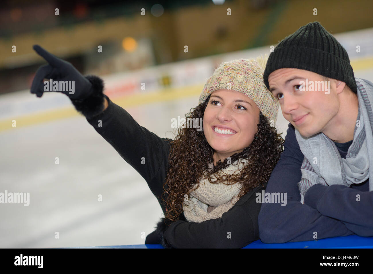 Young couple at ice rink pointing upwards Stock Photo - Alamy