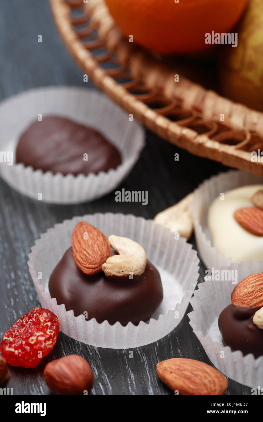 Few chocolate candies and nuts on wooden table Stock Photo - Alamy