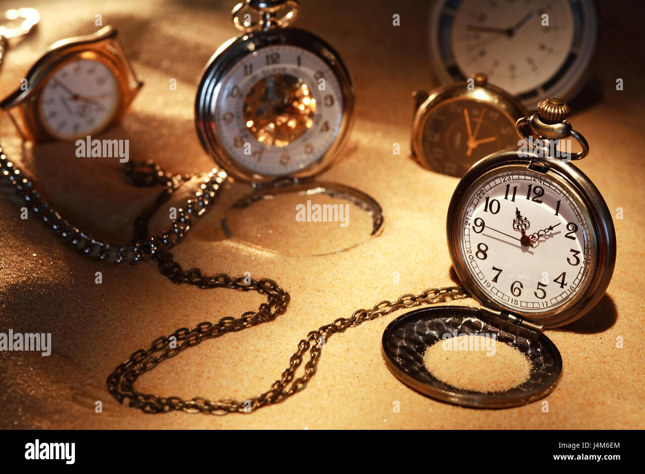Few watches on sand background with light beam and shadow Stock Photo ...