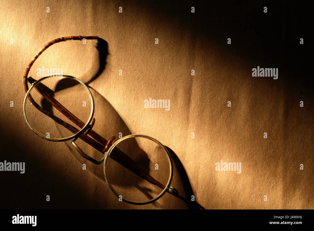 Old spectacles on paper surface under beam of light Stock Photo - Alamy