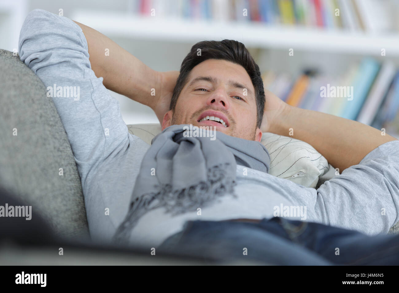 man laying on sofa relaxing Stock Photo - Alamy