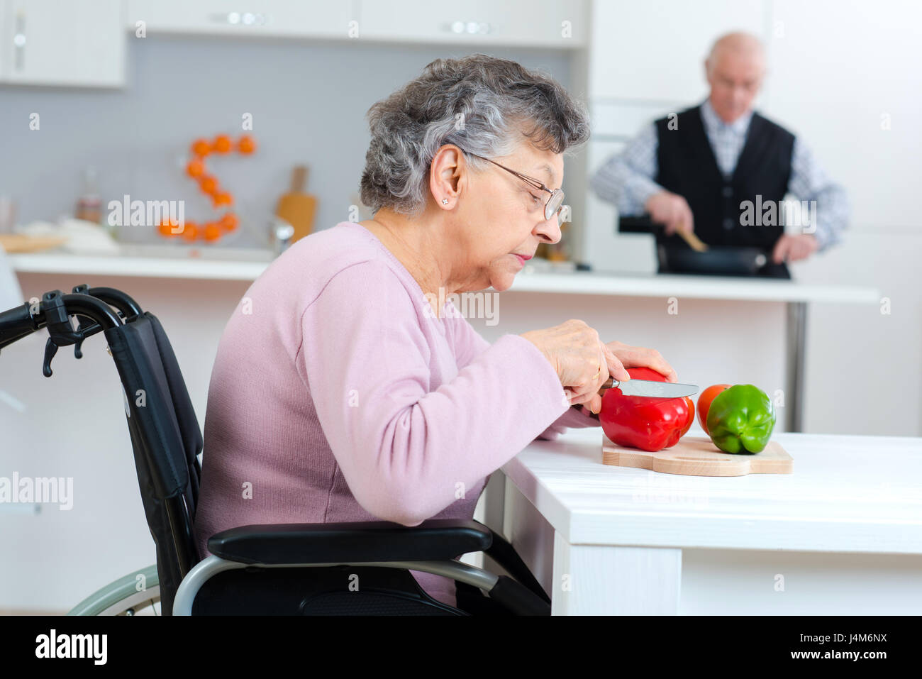 Disabled elderly lady sat at table chopping peppers Stock Photo - Alamy
