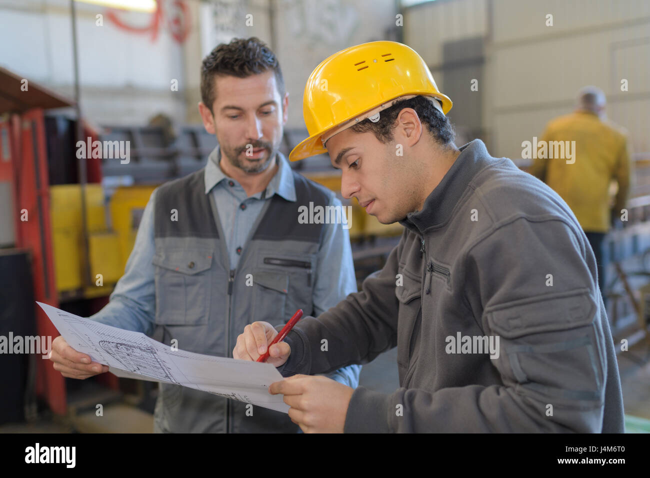 worker in uniform showing his boss the plan of factory Stock Photo - Alamy