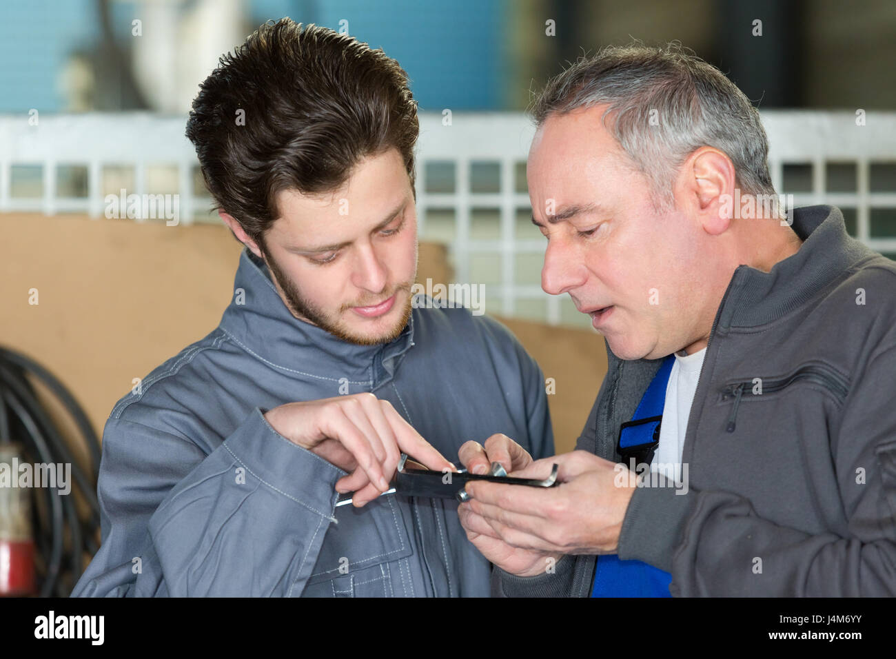 workmen inserting screw into metal plate Stock Photo - Alamy