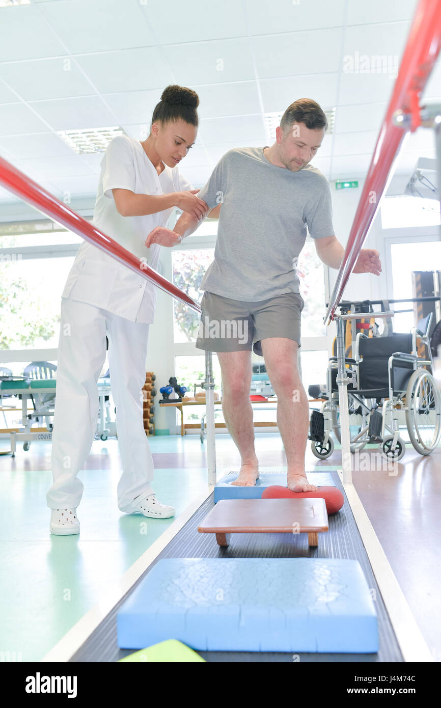 Physiotherapist helping man to walk Stock Photo - Alamy