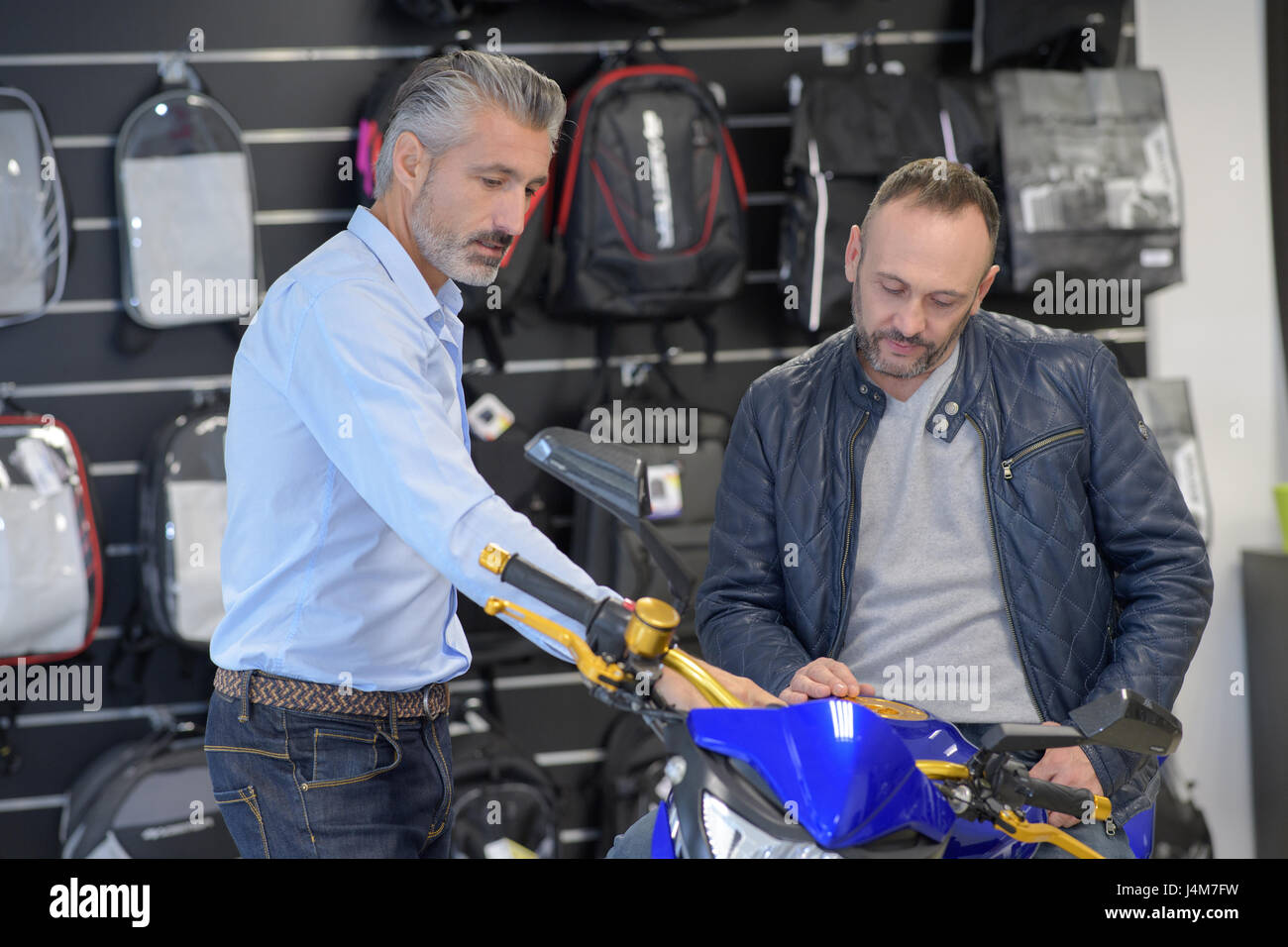 Men looking at motorcycle in showroom Stock Photo - Alamy