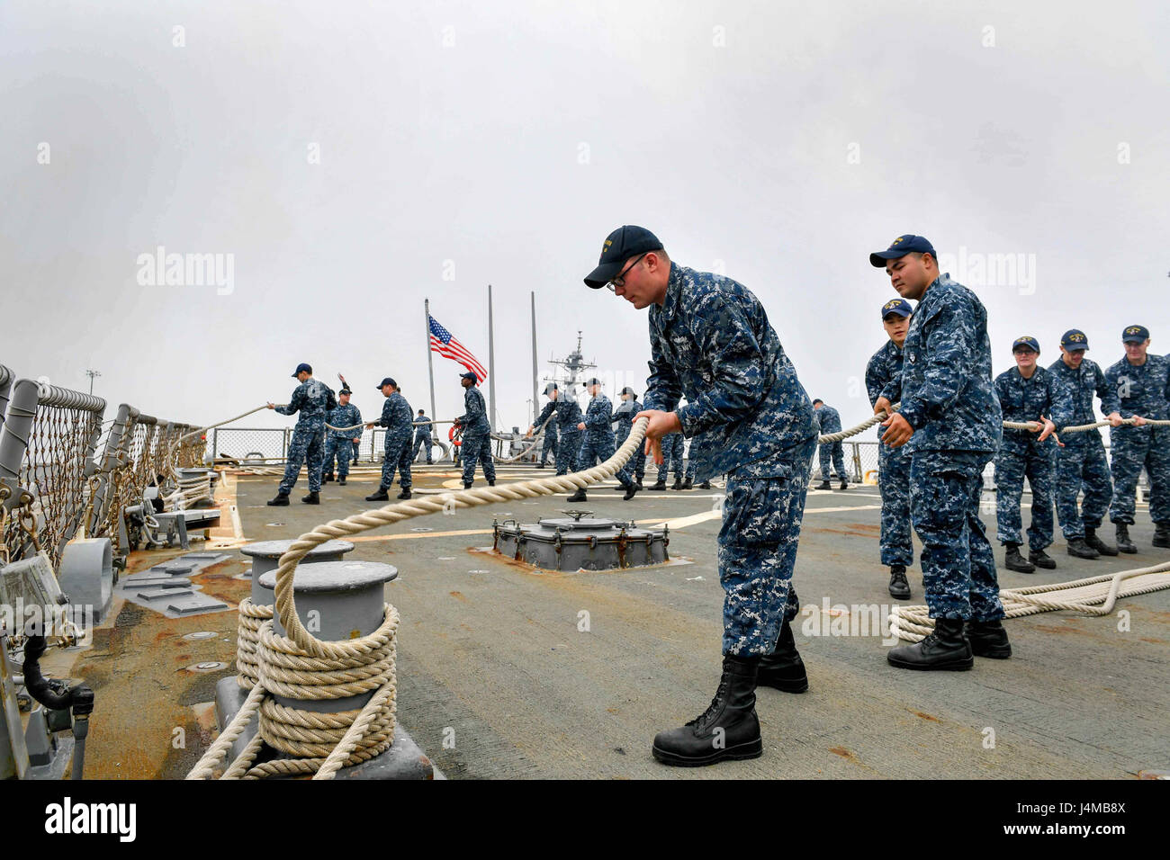 Sailors aboard USS Laboon (DDG 58) manage mooring lines while preparing ...