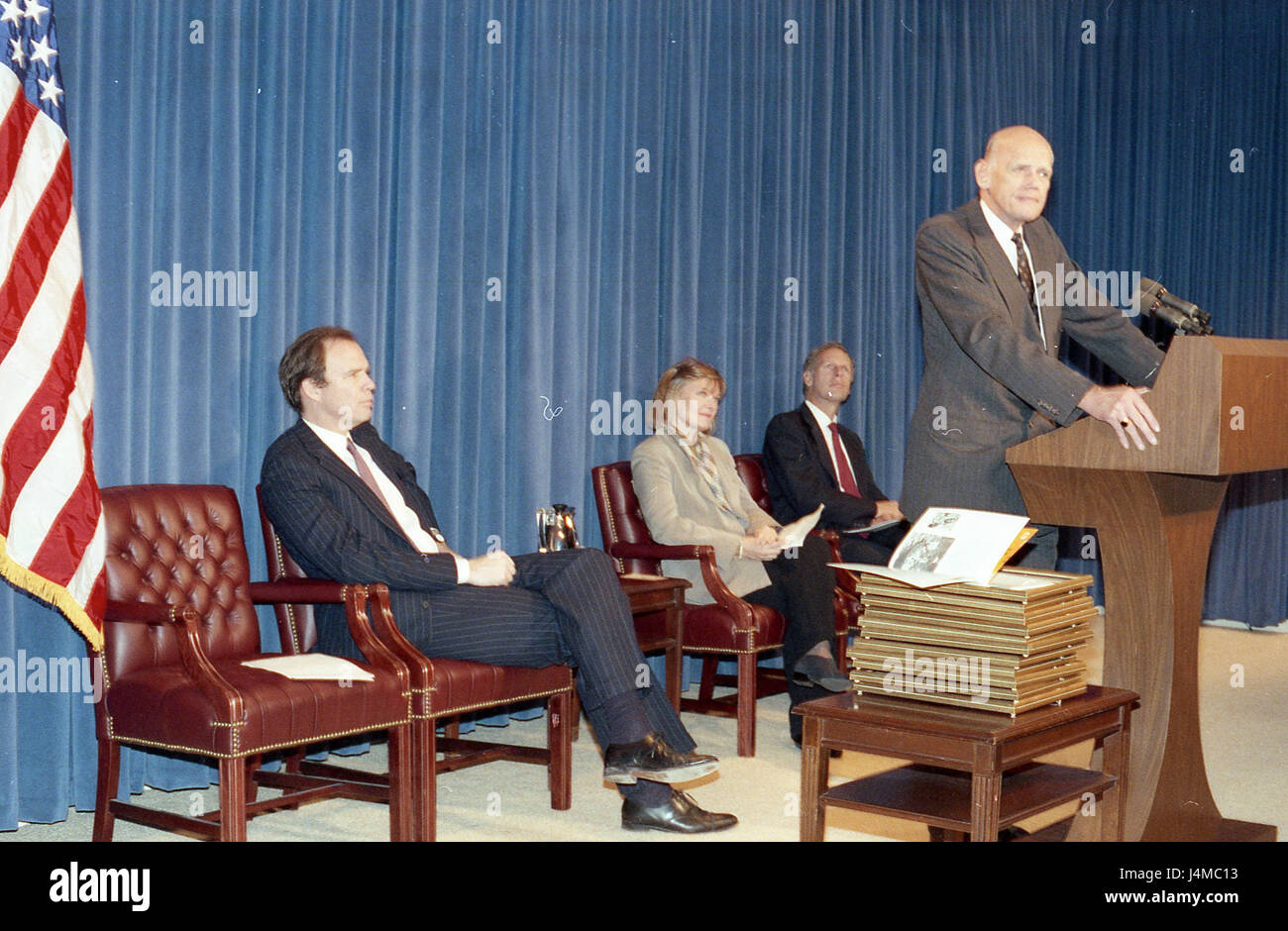 A MAN IS STANDING AT THE PODIUM GIVING A SPEECH WITH OTHER PEOPLE ...