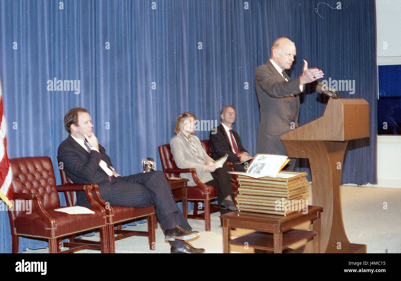 A MAN IS STANDING AT THE PODIUM GIVING A SPEECH WITH OTHER PEOPLE ...