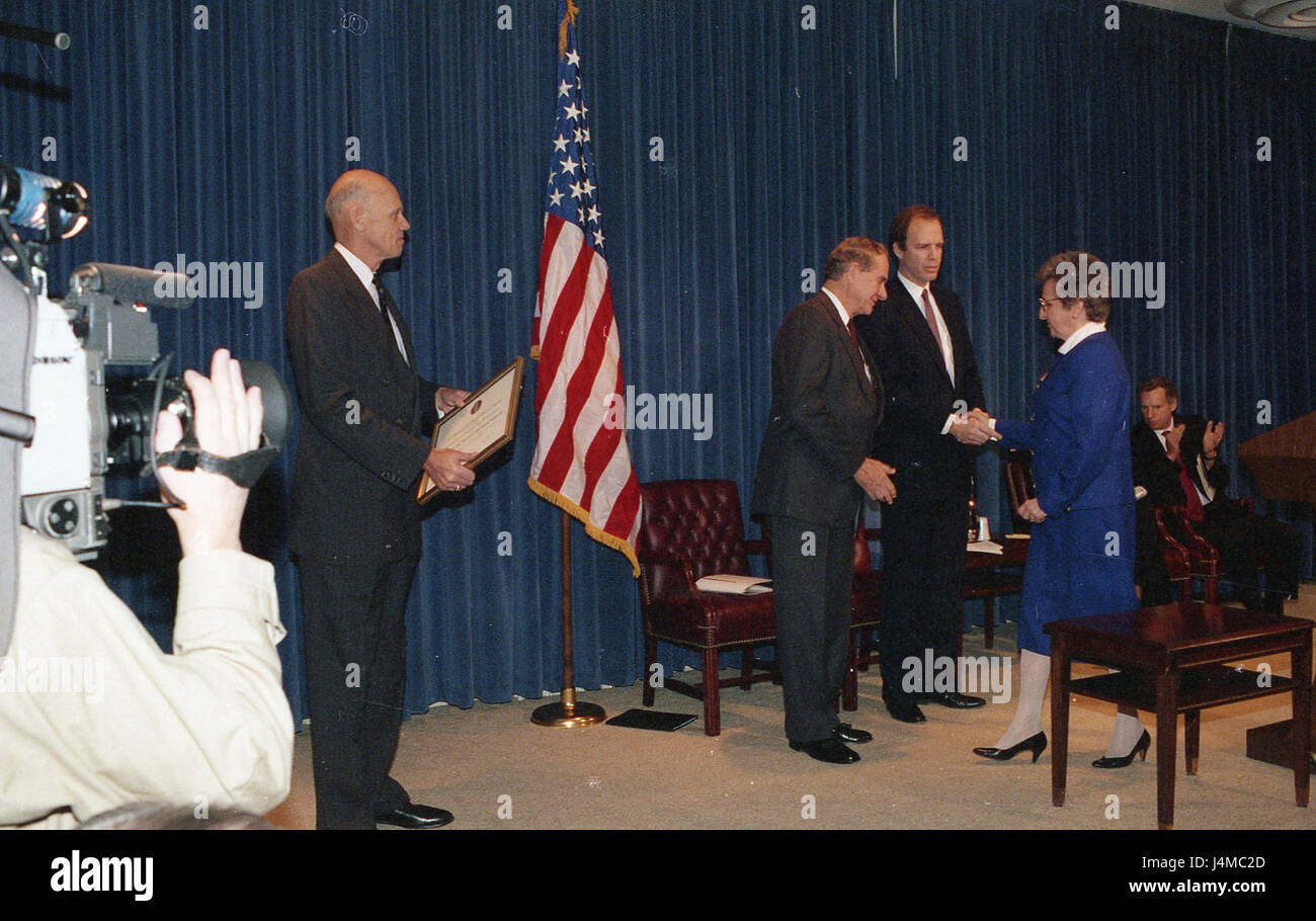 A WOMEN IS AT THE PODIUM GREETING TWO MEN WITH OTHER PEOPLE LOOKING ...