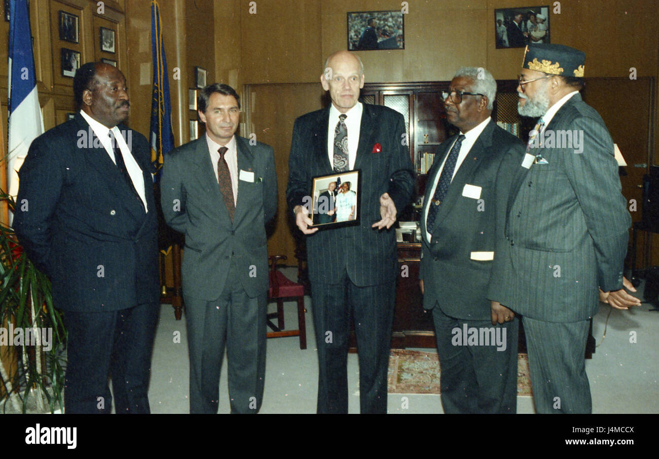 FIVE MEN ARE STANDING IN THE OFFICE HAVING CONVERSATION ABOUT A PICTURE ...