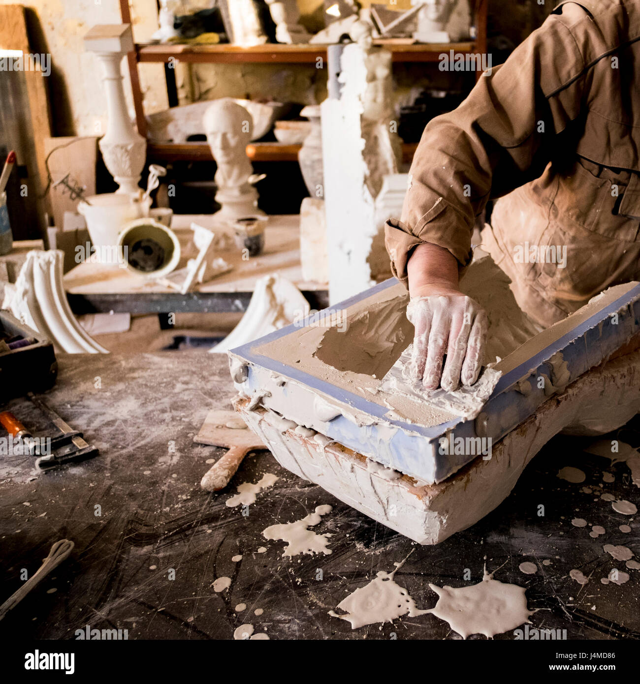 Caucasian artist scraping plaster in mold Stock Photo - Alamy