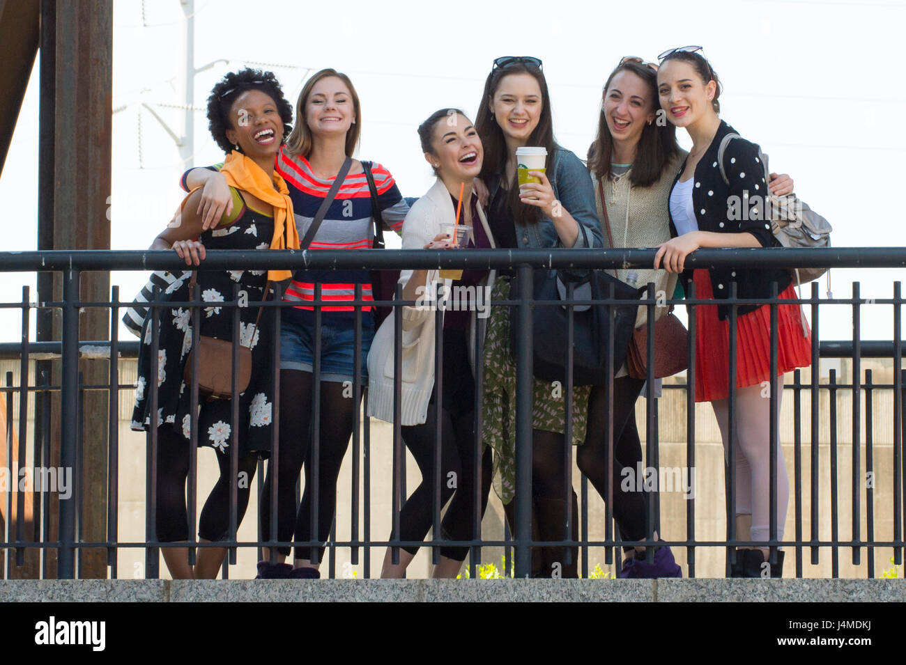 Portrait of smiling women posing behind railing Stock Photo - Alamy