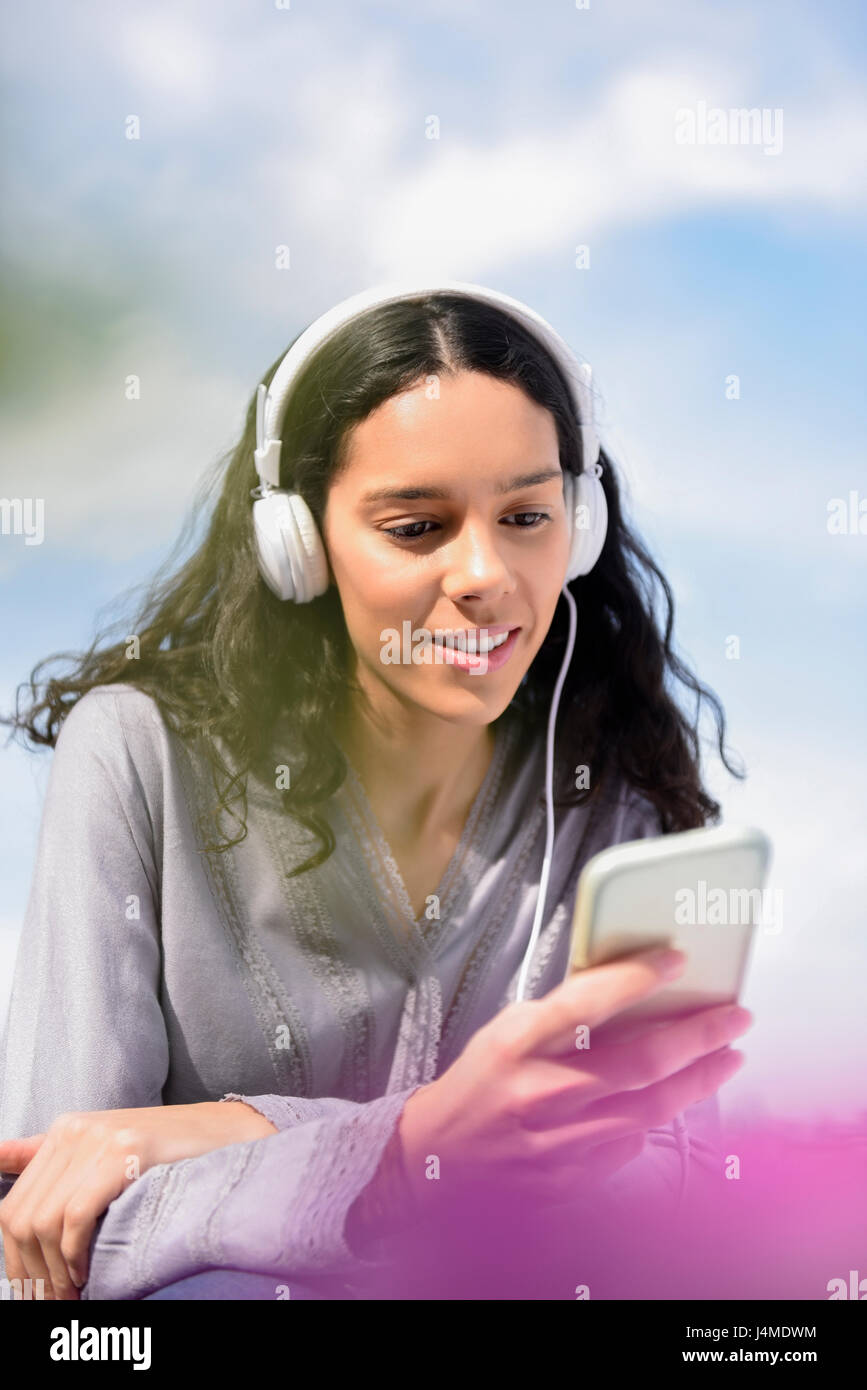 Hispanic woman listening to cell phone with headphones Stock Photo - Alamy