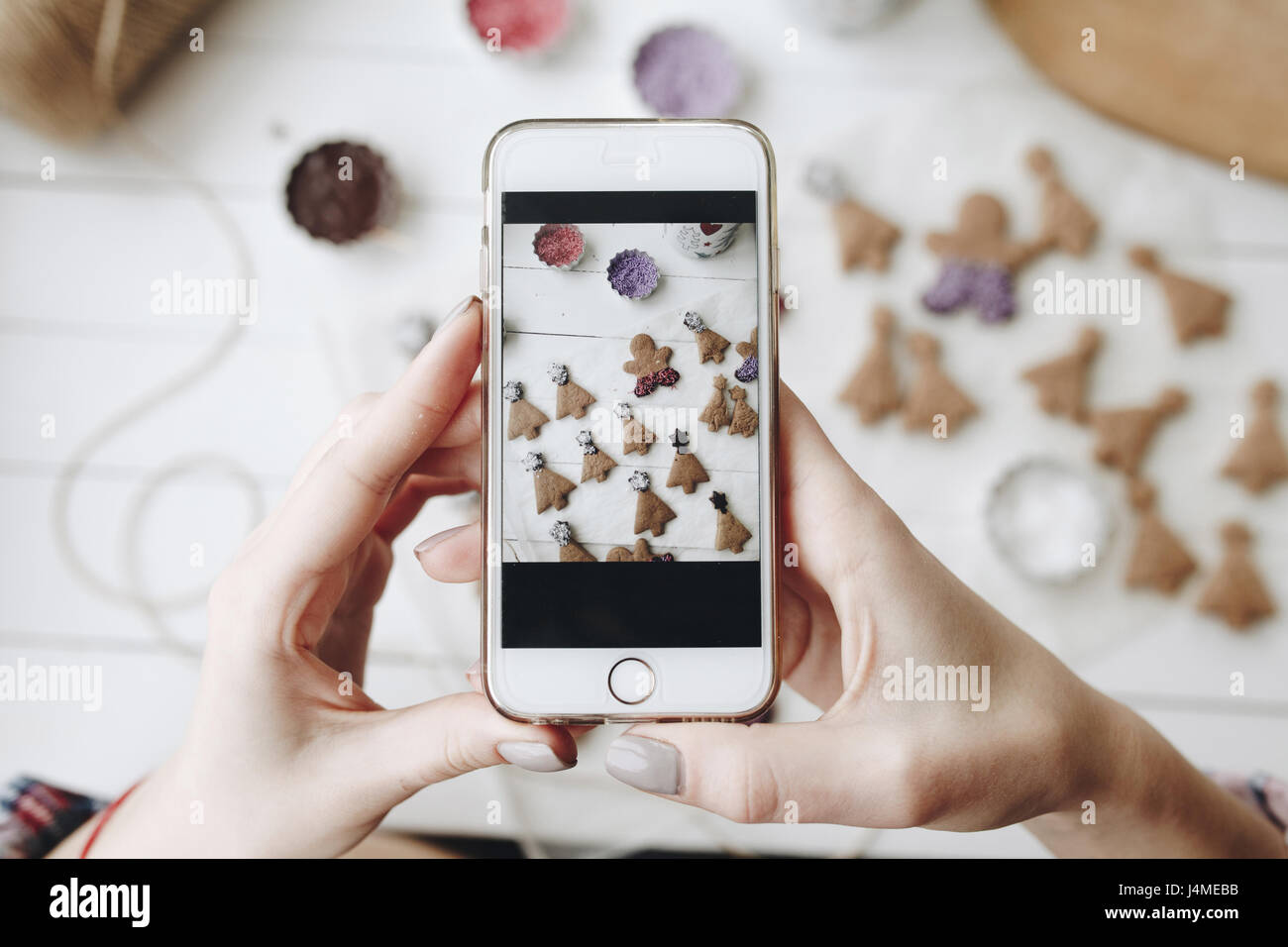 Hands of Caucasian woman photographing Christmas cookies with cell ...
