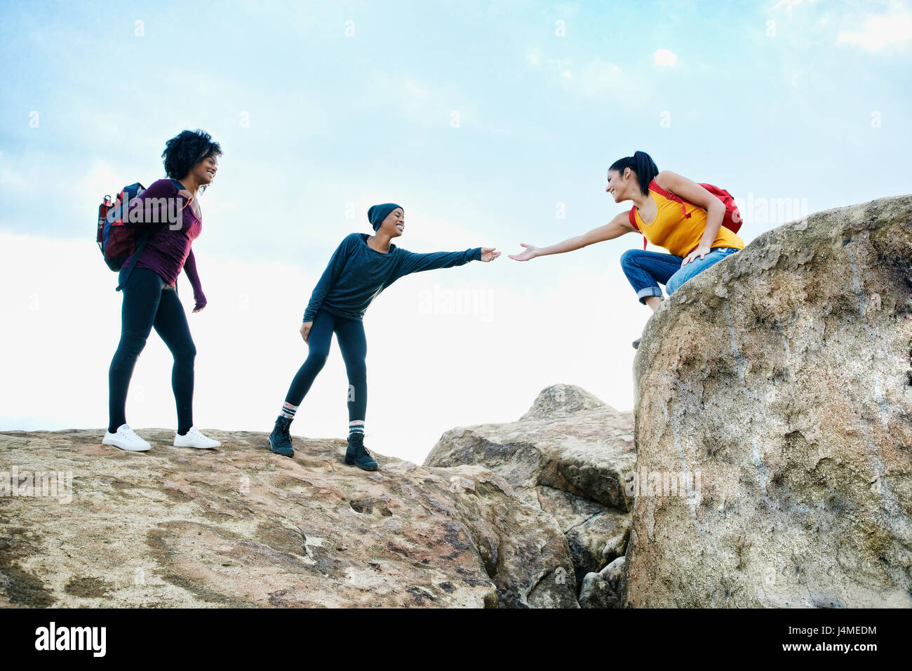 Woman helping friend hiking on rock formation Stock Photo - Alamy