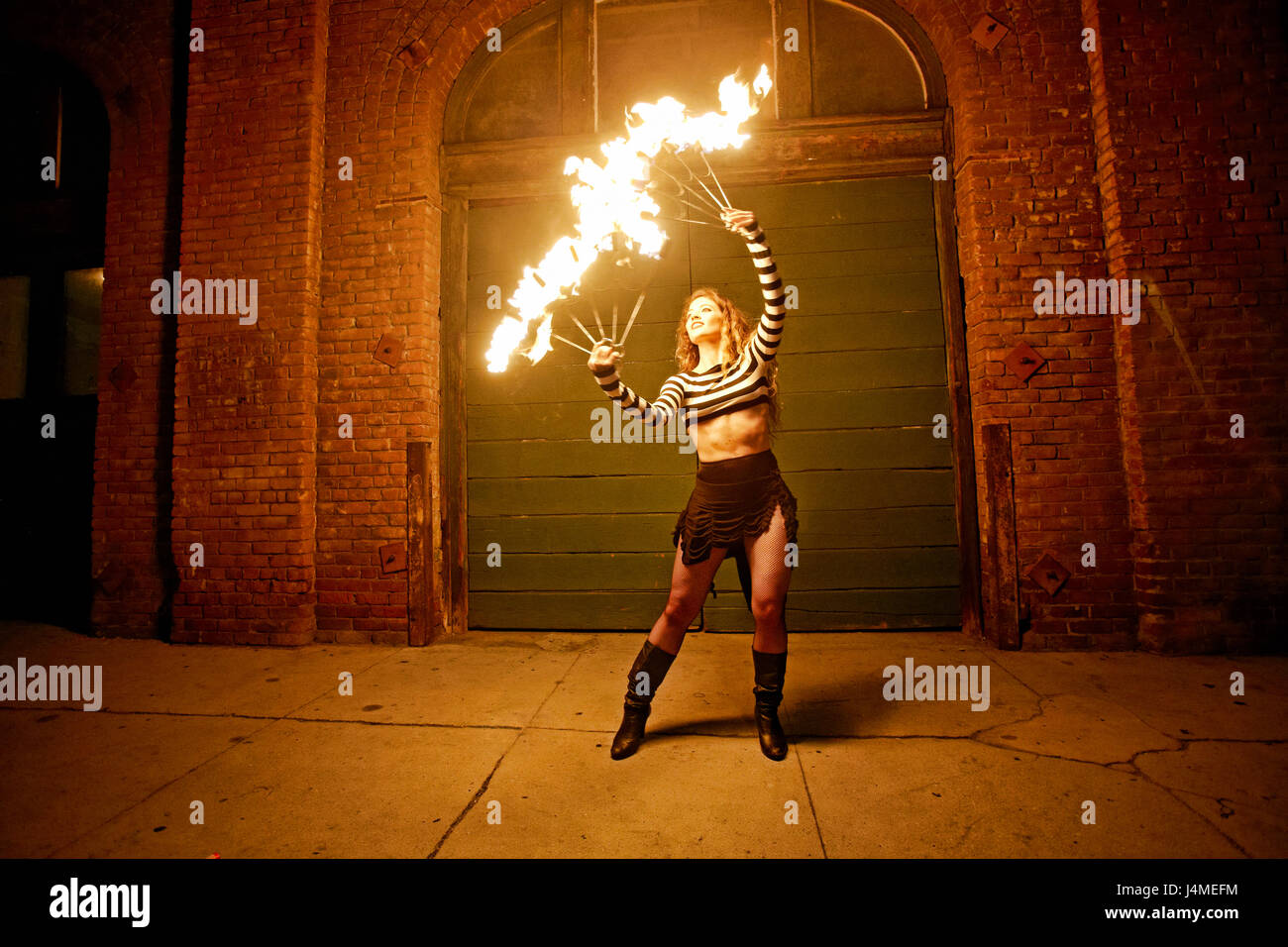 Caucasian woman juggling fire on city sidewalk at night Stock Photo - Alamy