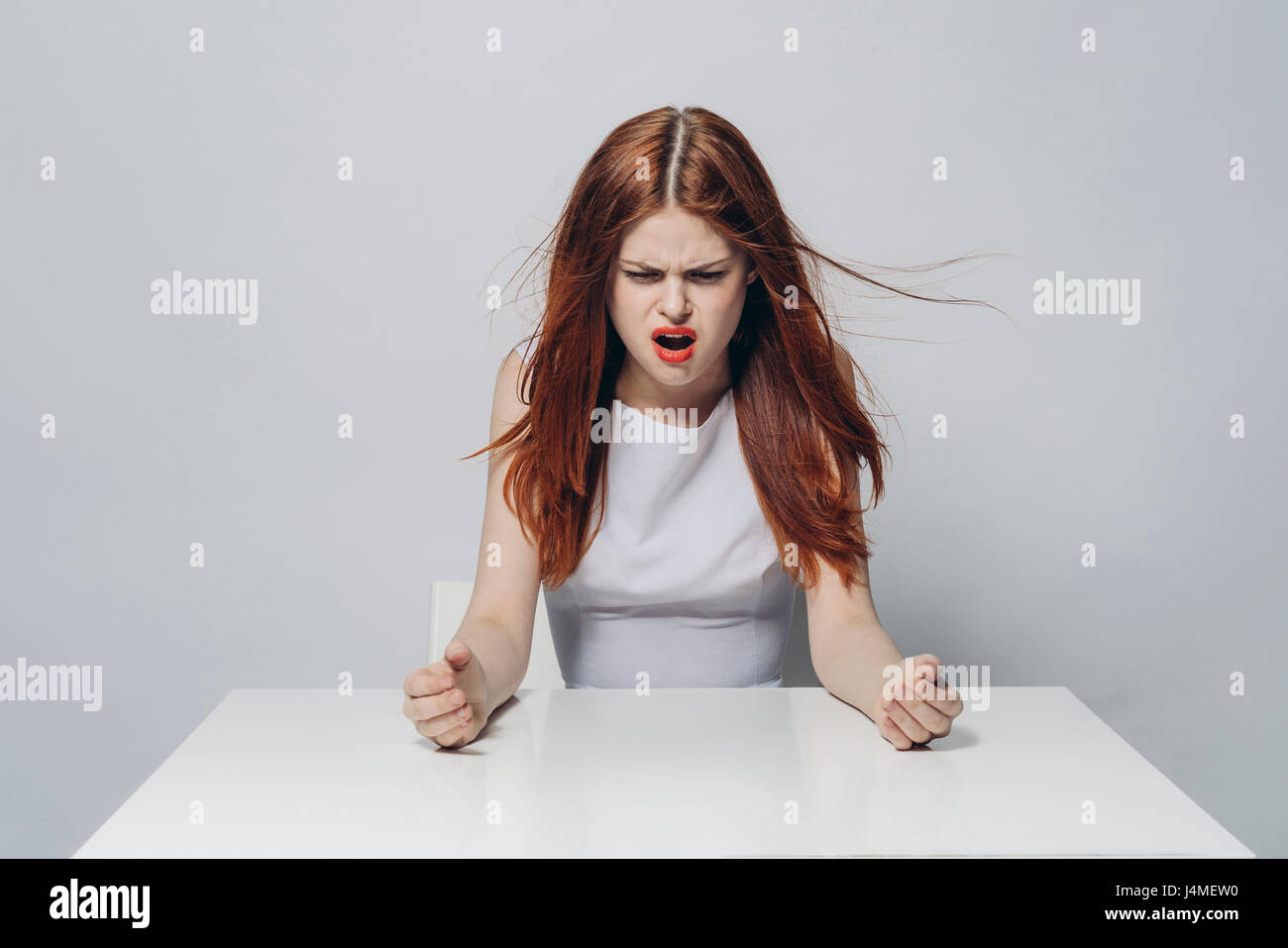 Angry Caucasian woman sitting at windy table Stock Photo - Alamy