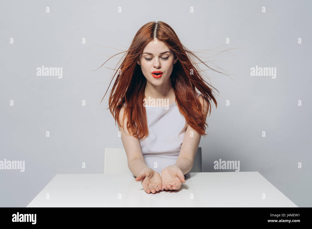 Hopeful Caucasian woman sitting at windy table Stock Photo - Alamy