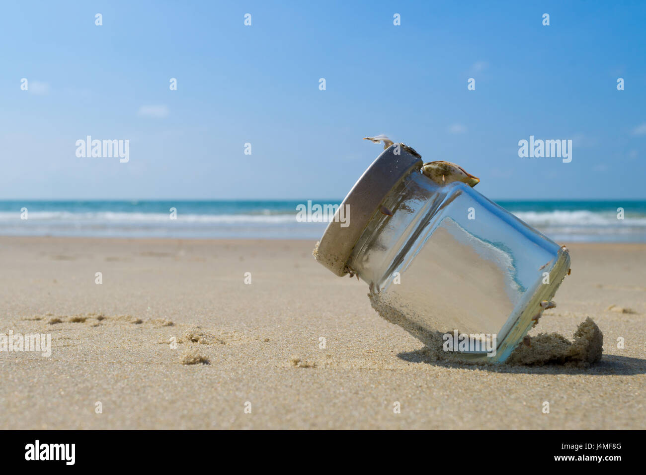Empty glass bottle on sandy beach with blue sky and sea Stock Photo - Alamy